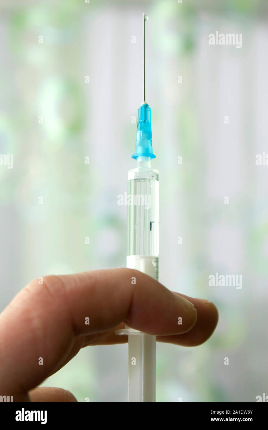 Fingers of the doctor with a syringe and an ampoule which types a ...