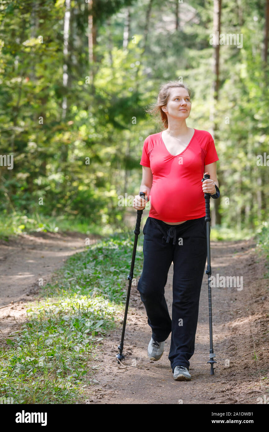 Young pregnant woman walking along a trail through the forest during ...