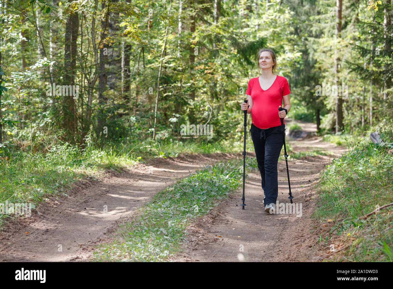 Young pregnant woman walking along a trail through the forest during ...