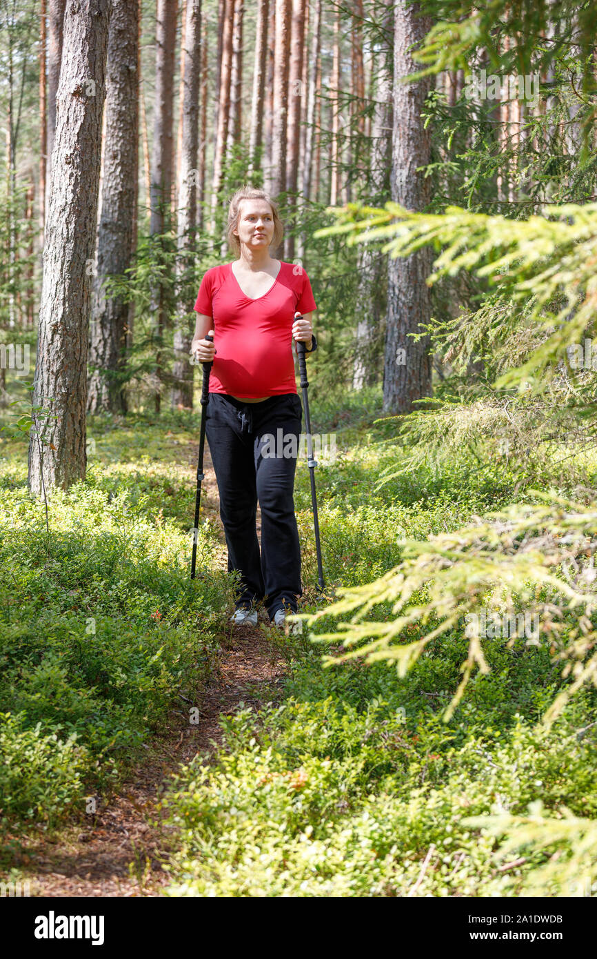 Young pregnant woman walking along a trail through the forest during ...