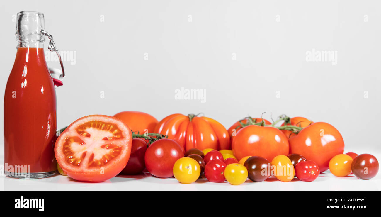 panorama with various tomatoes and a bottle in front of a white and ...