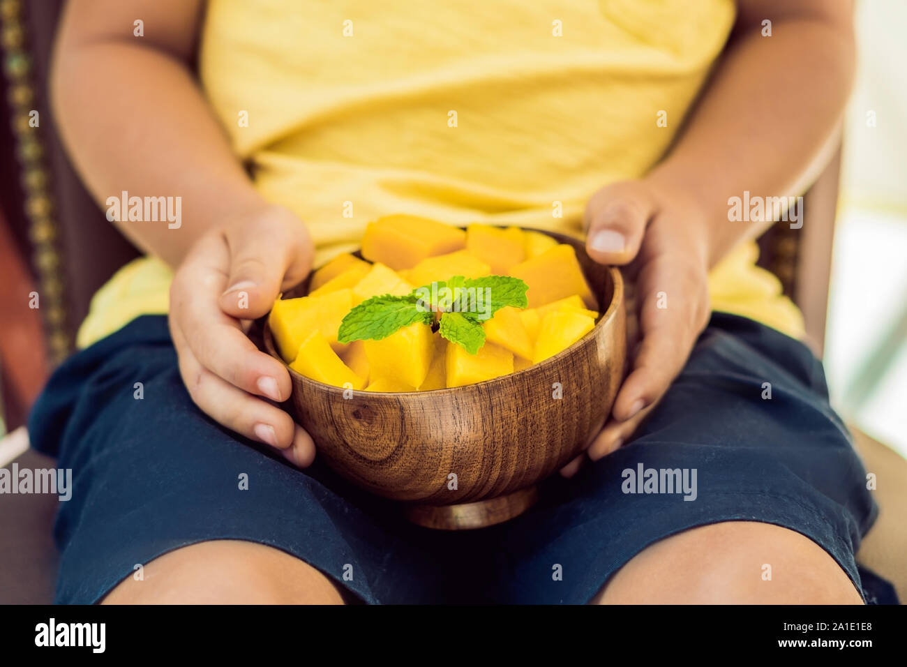 Little cute boy eating mango on the terrace Stock Photo - Alamy