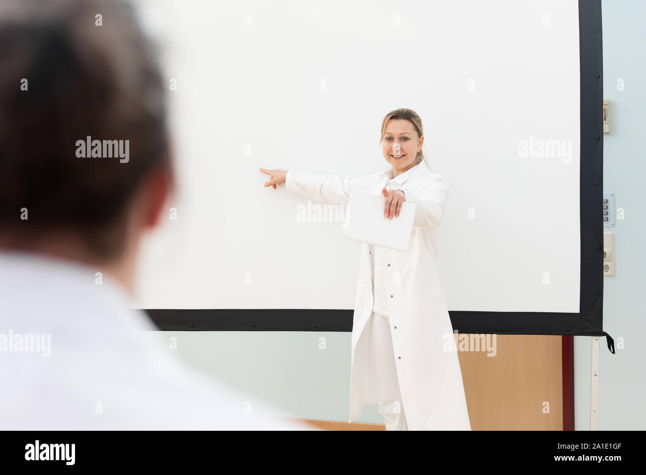 female doctor is pointing to an empty white screen Stock Photo - Alamy