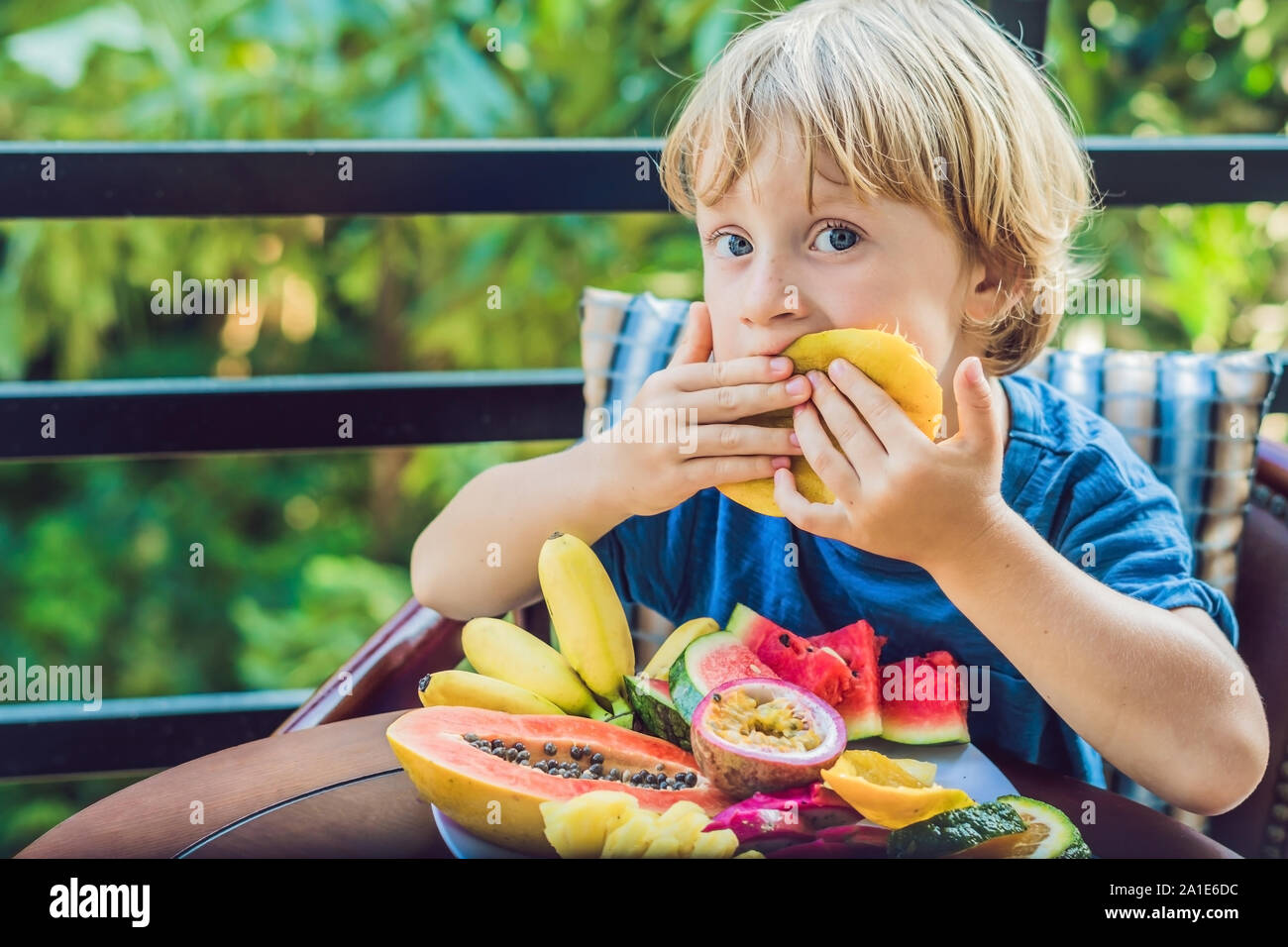The boy is eating different fruits on the terrace Stock Photo - Alamy