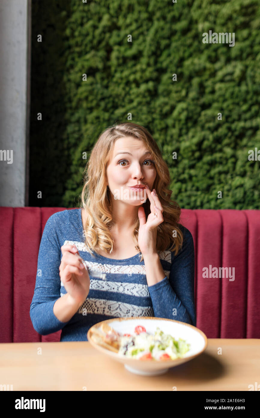 Blonde pretty woman eating salad. Client tasting delicious meal in a ...