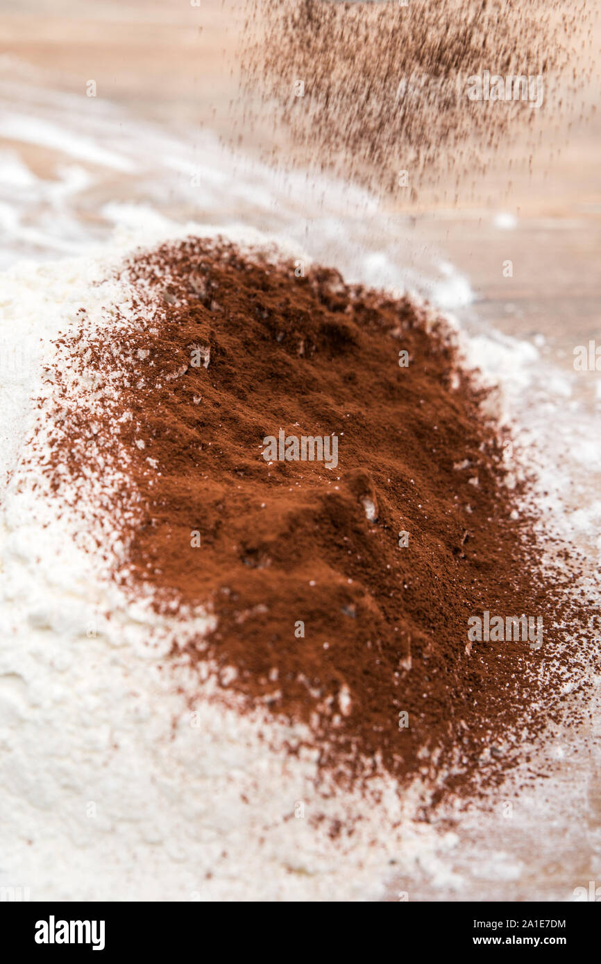 Cocoa powder sifting into white flour, details of a bakery process ...