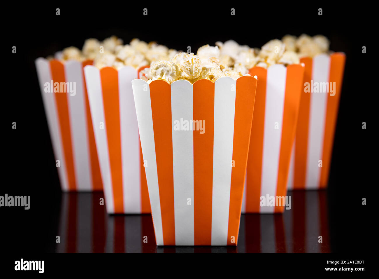 orange striped box with popcorn, black background, concept snack for a ...