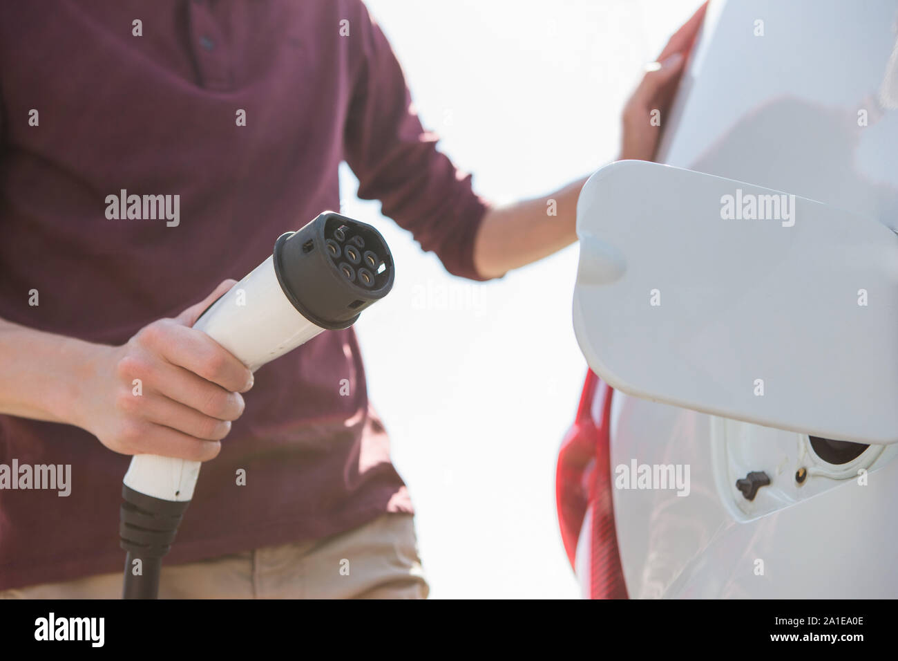 Man is standing near the electric car. The car is charging at the ...