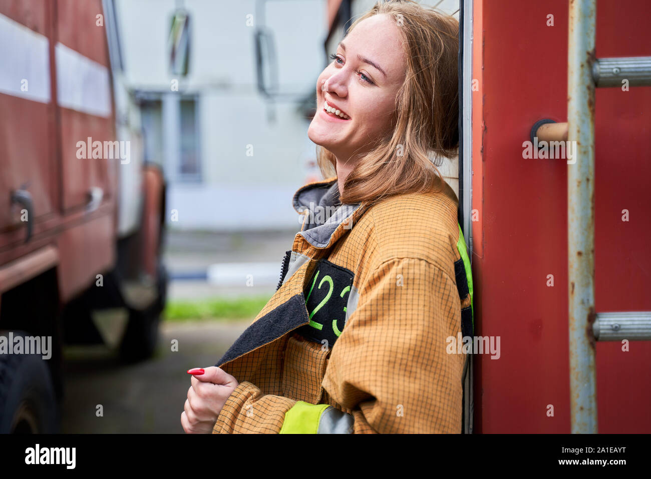 Photo of firefighter woman next to fire engines on street on summer day ...