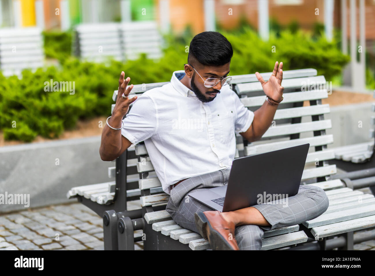 Indian sad and angry businessman in formal wear sitting on bench with ...