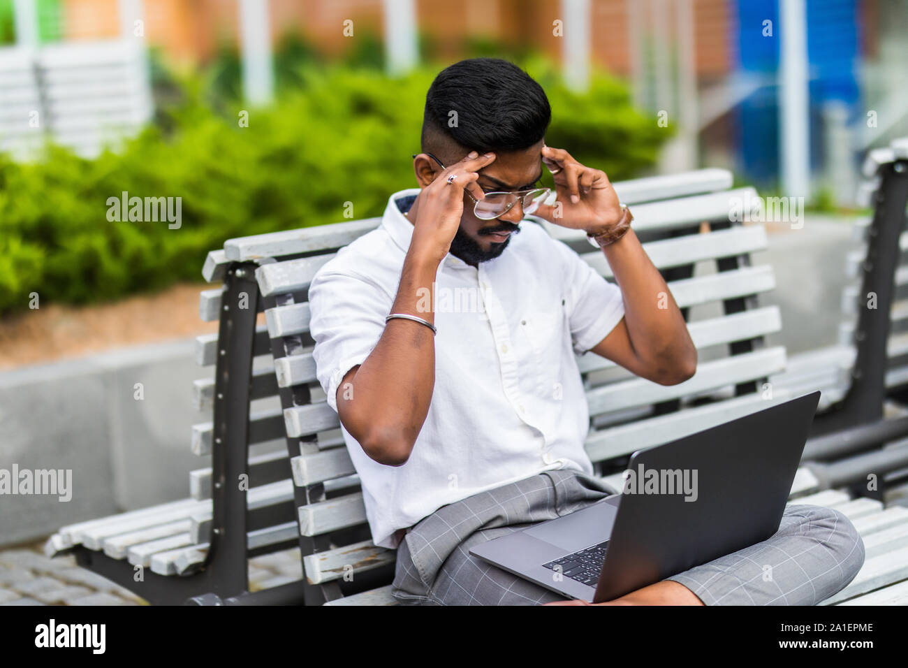 Indian sad and angry businessman in formal wear sitting on bench with ...