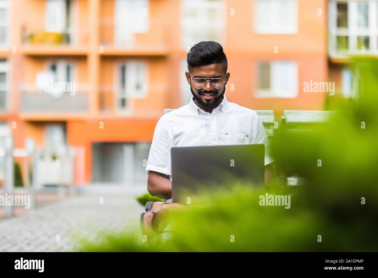 Full length of happy young businessman using laptop outside office ...