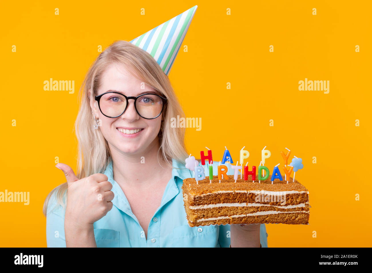 Positive funny young woman with a cap and a homemade cake in her hands ...