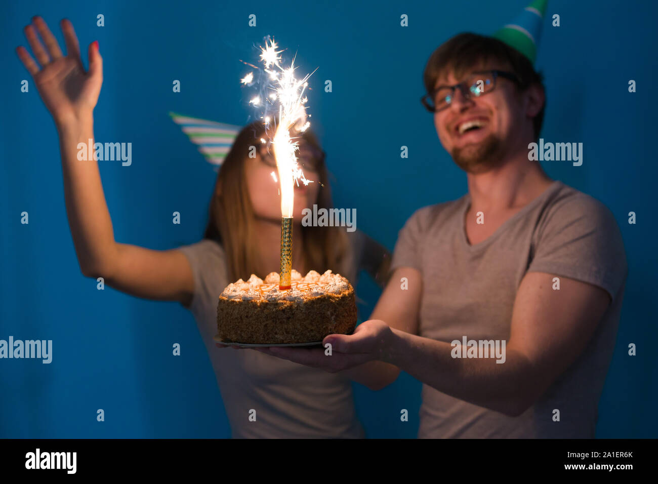 Cheerful young couple charming guy and cute girl in paper hats make ...