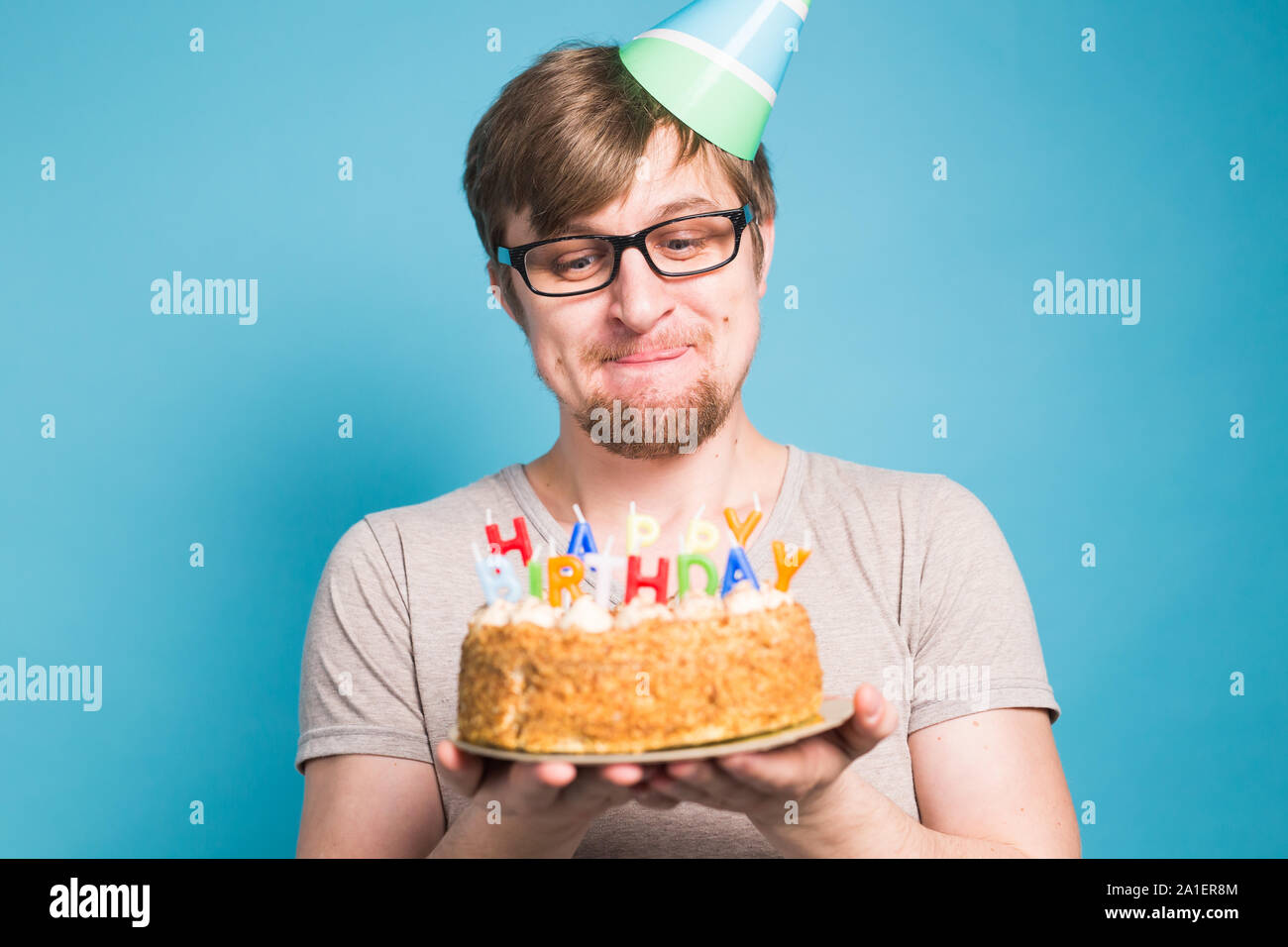 Crazy cheerful young man in glasses and paper congratulatory hats ...
