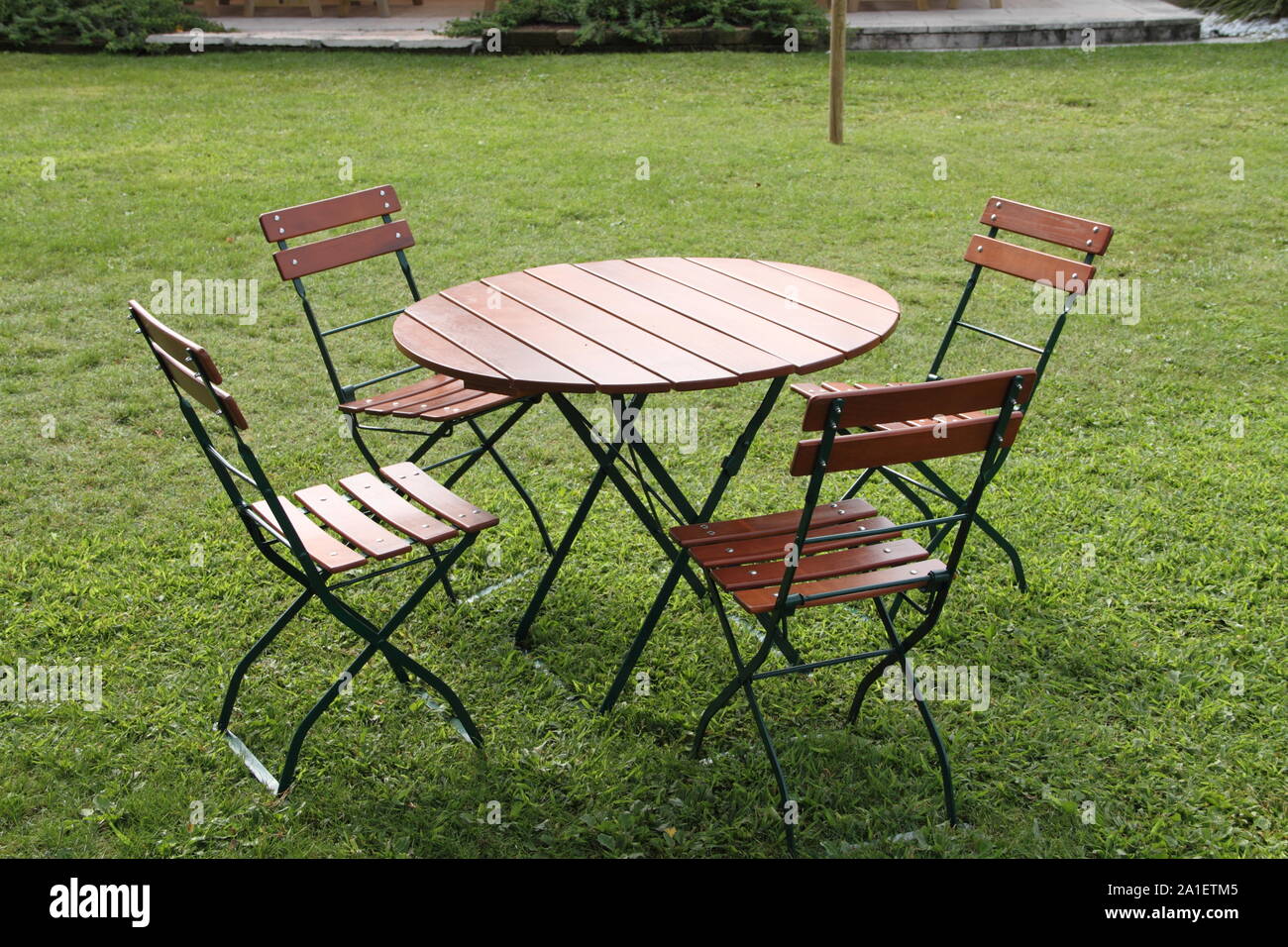 four empty chairs and a round table in the garden Stock Photo - Alamy