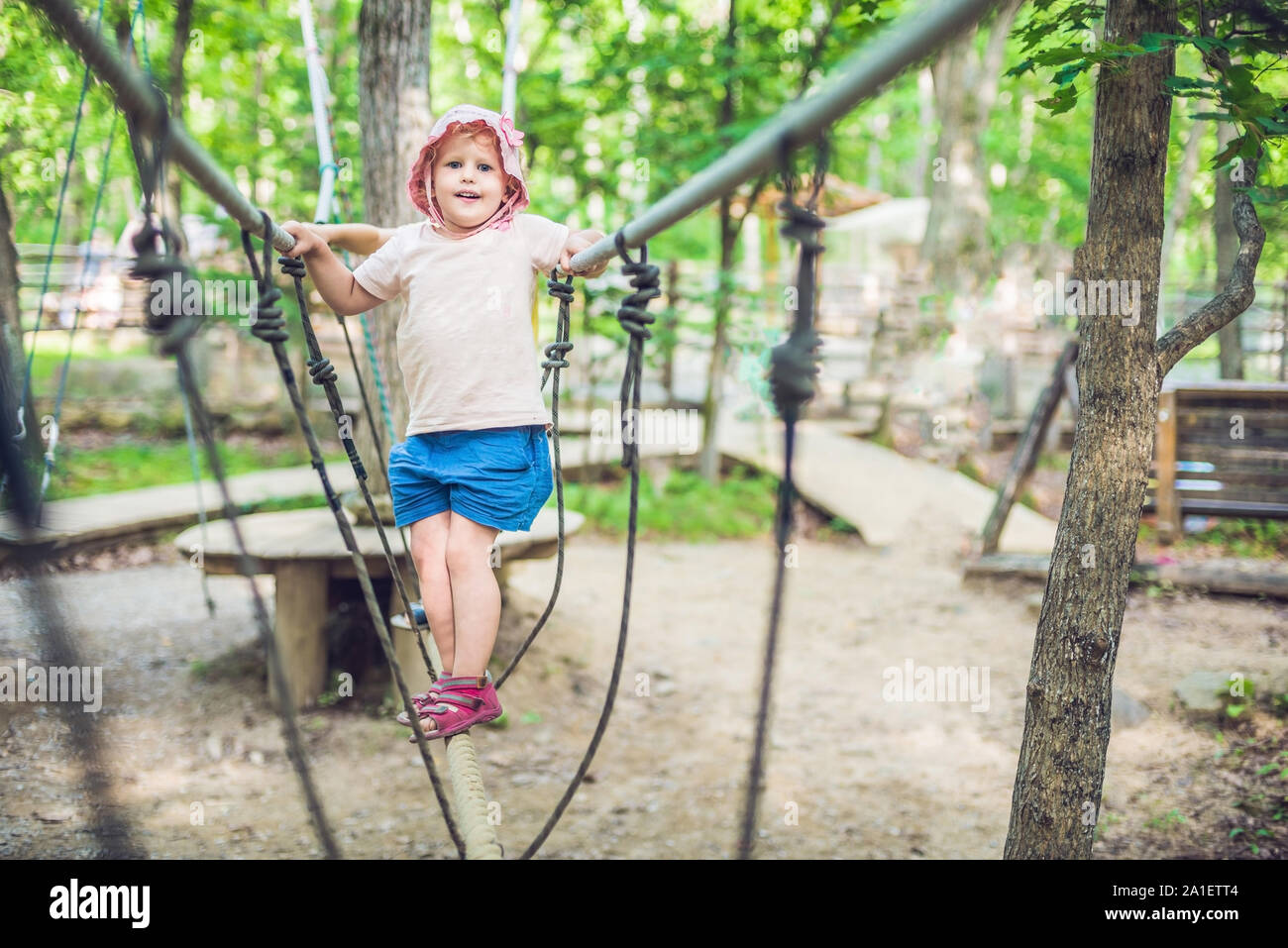 Portrait of cute little boy and girl walk on a rope bridge in an ...