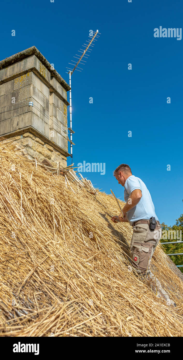 A Master Thatcher working on the roof of a village cottage repairing ...