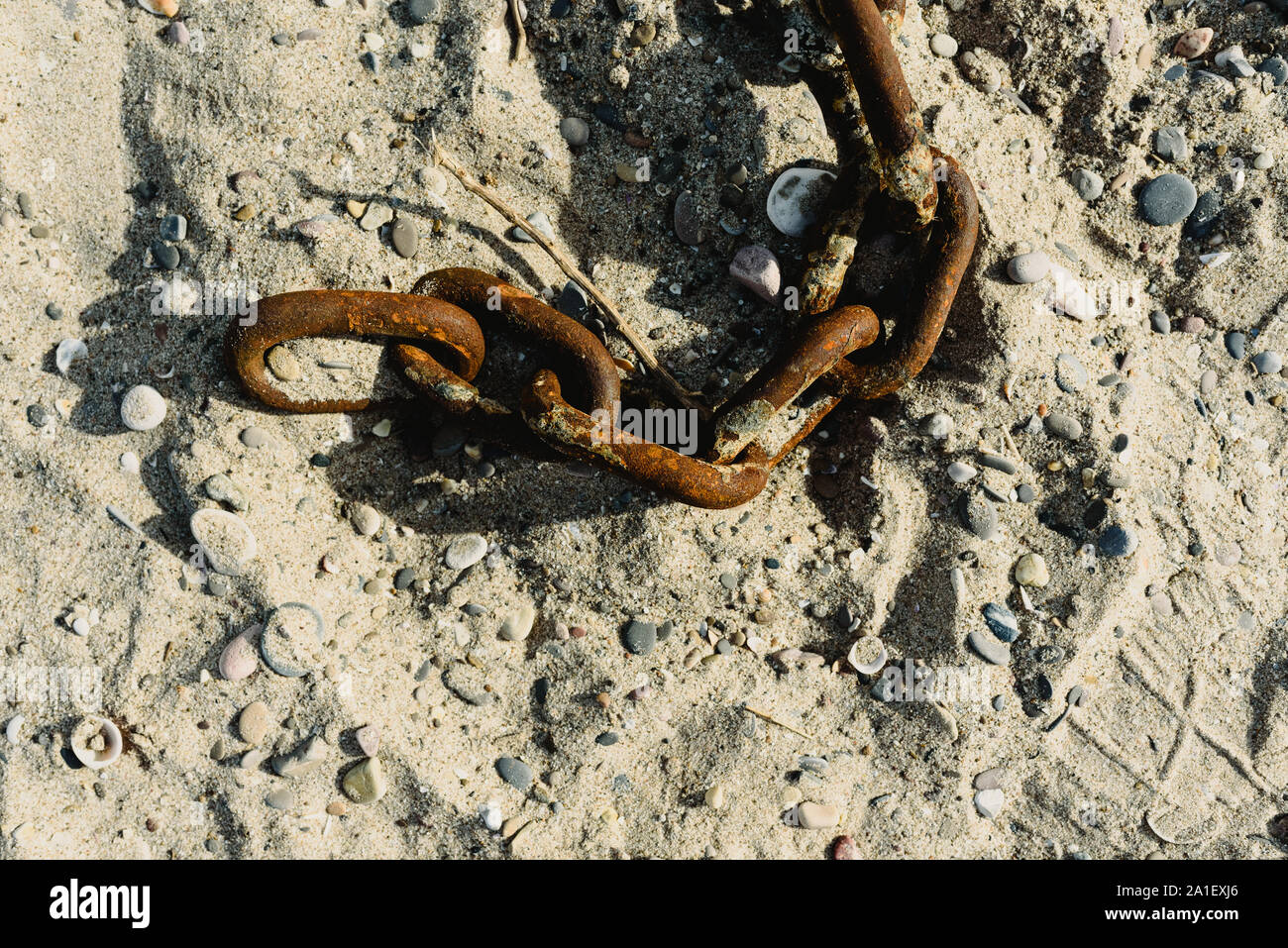 Concept of abandonment, old rusty and broken chains thrown in the sand ...