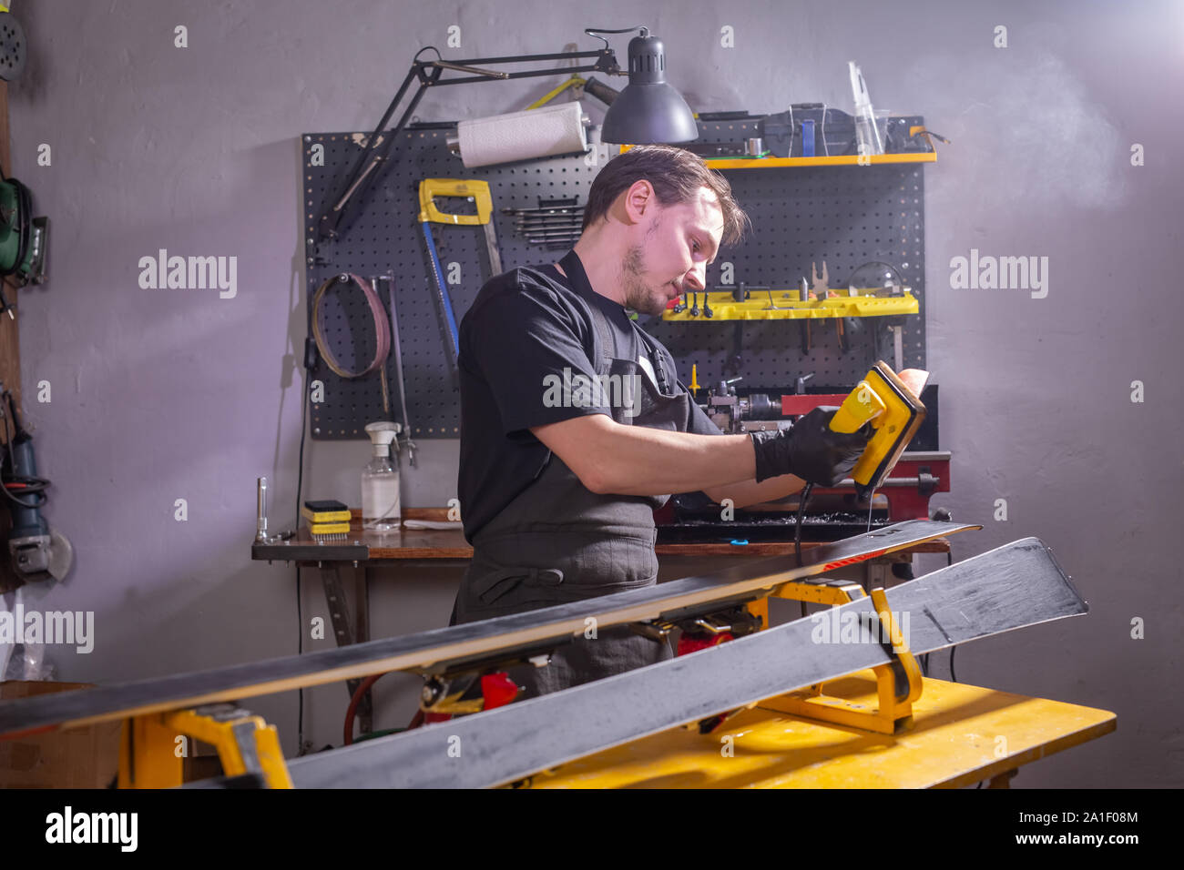Repair, people concept - mechanic, man is rubbing a ski Stock Photo - Alamy