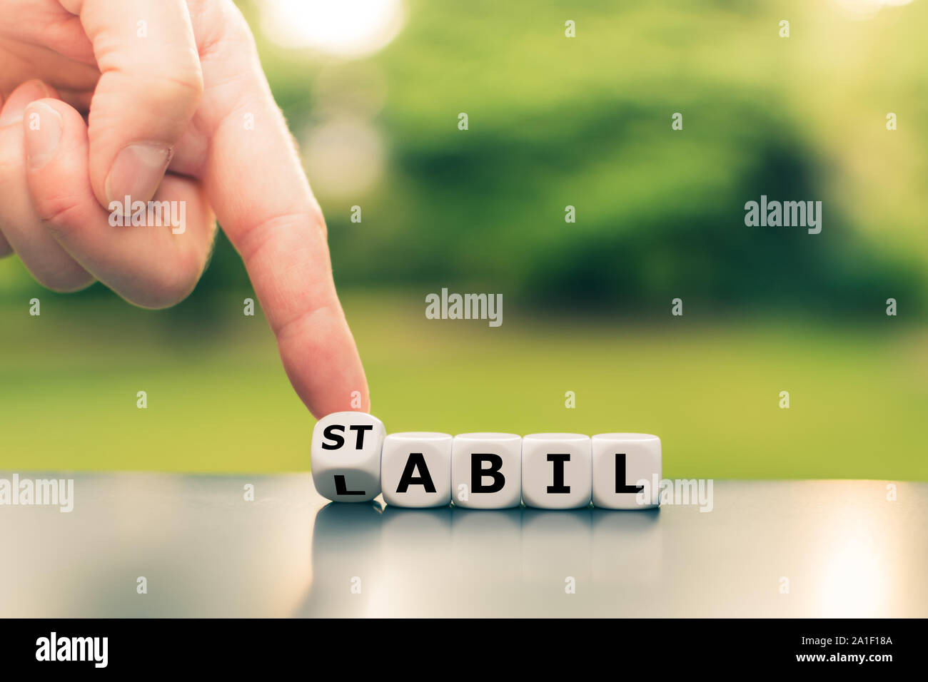 Hand turns a dice and changes the German word "labil" ("unstable" in ...