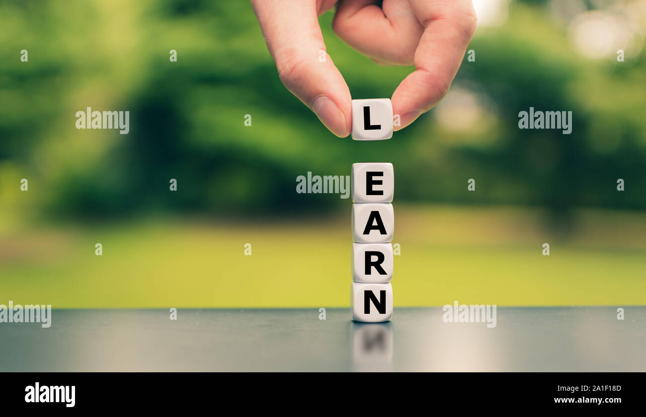 Learn or earn? Hand lifts a dice and changes the word "learn" to "earn ...