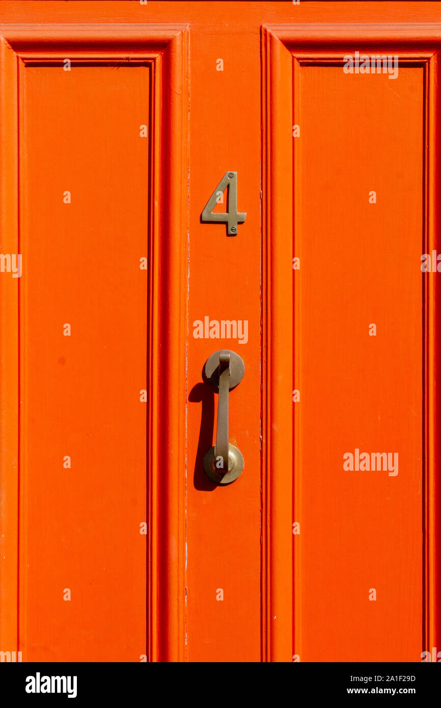 House number 4 on a bright orange wooden front door Stock Photo - Alamy