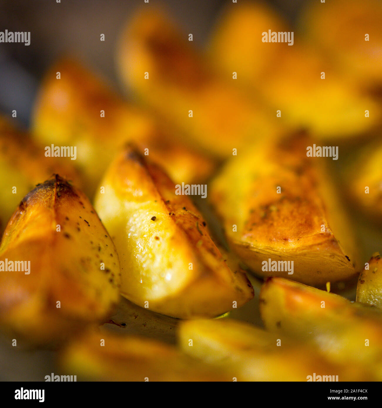 ready baked potato slices with spices lie in rows after oven close up ...