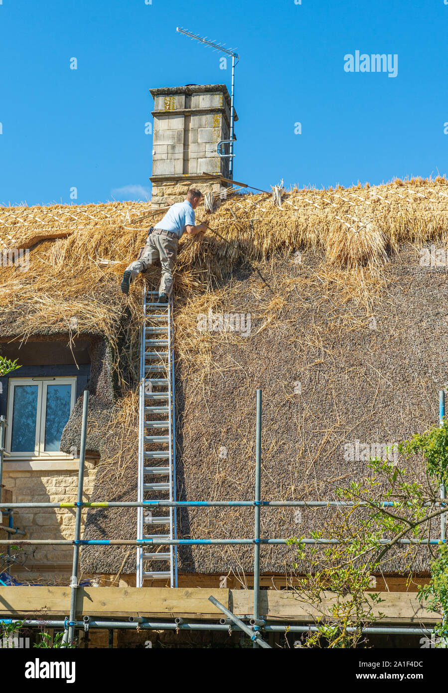 A Master Thatcher working on the roof of a village cottage repairing ...