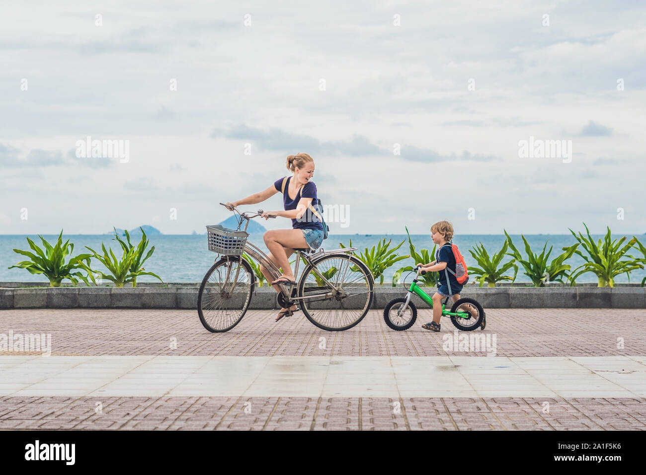 Happy family is riding bikes outdoors and smiling. Mom on a bike and ...