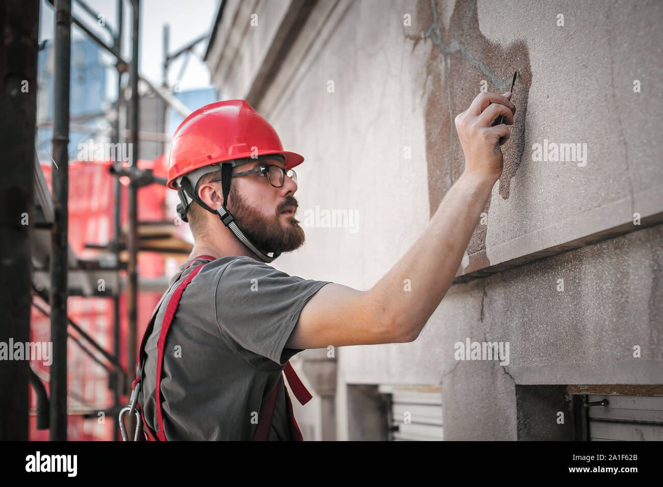 Man worker standing on scaffolding, perform work on the restoration of ...