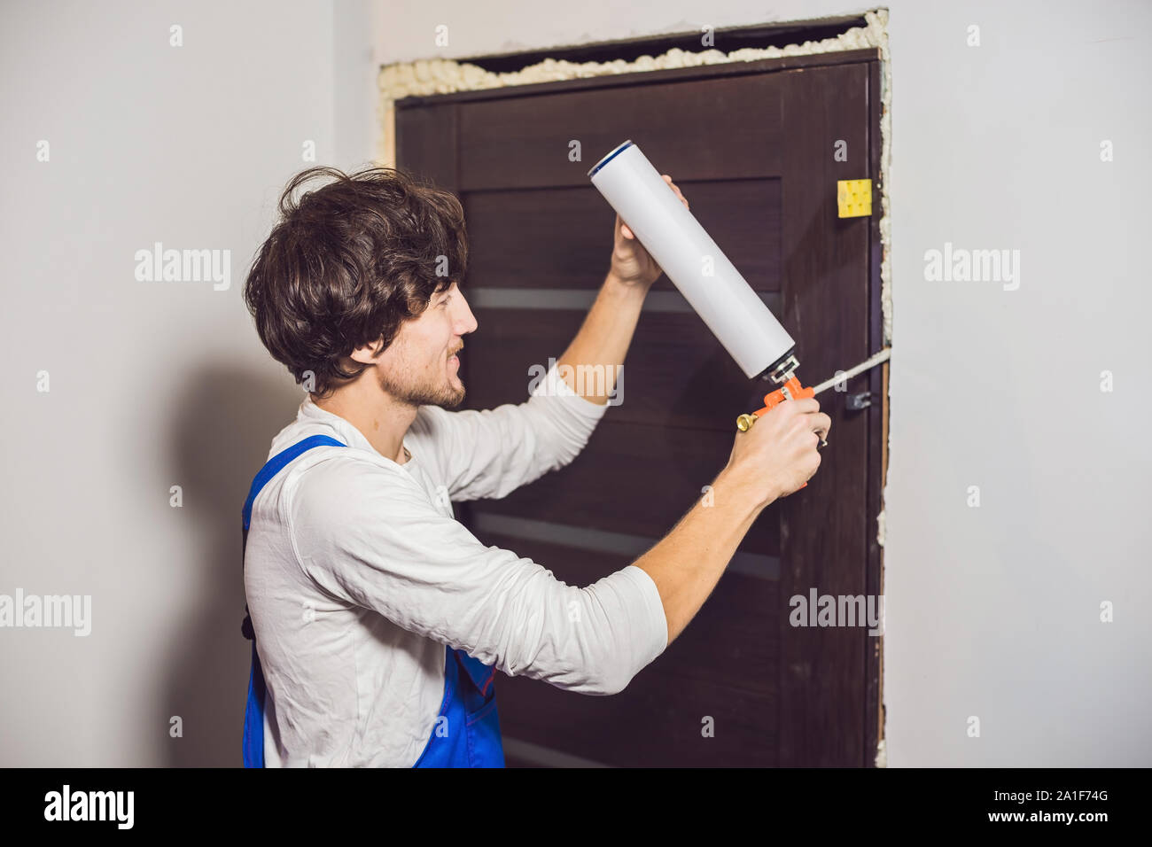 Young handyman installing door with an mounting foam in a room Stock ...