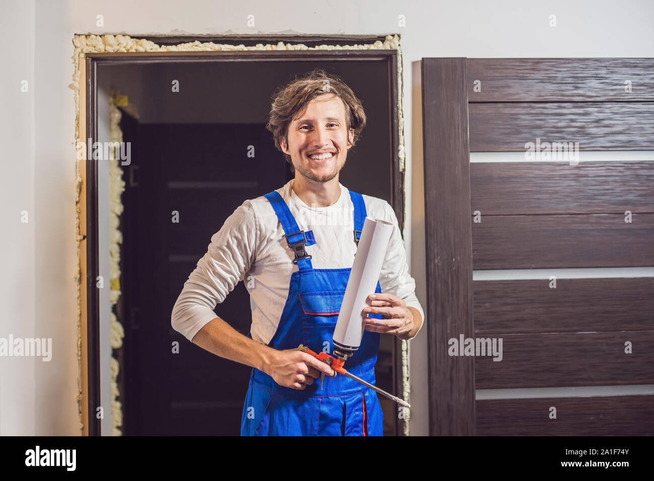 Young handyman installing door with an mounting foam in a room Stock ...