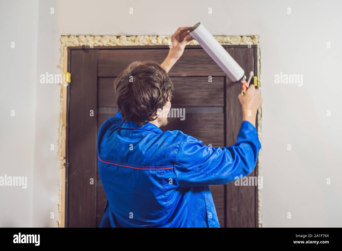 Young handyman installing door with an mounting foam in a room Stock ...