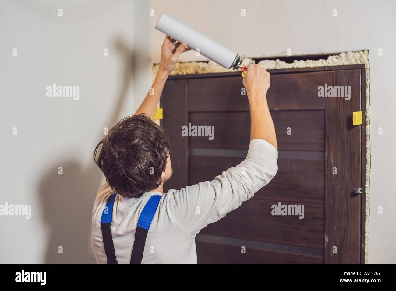 Young handyman installing door with an mounting foam in a room Stock ...