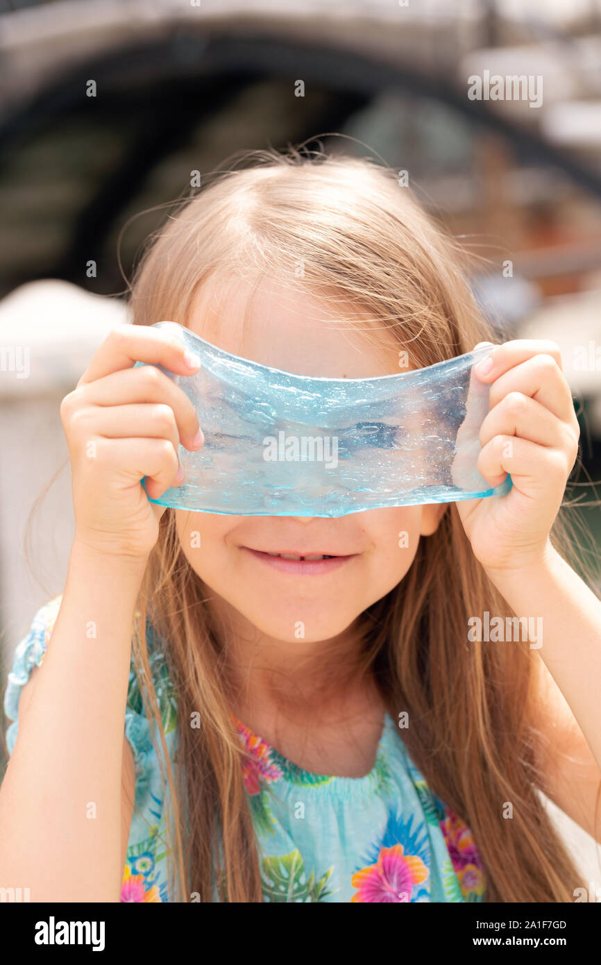 Girl stretches before eyes, face, transparent turquoise slime. Against ...