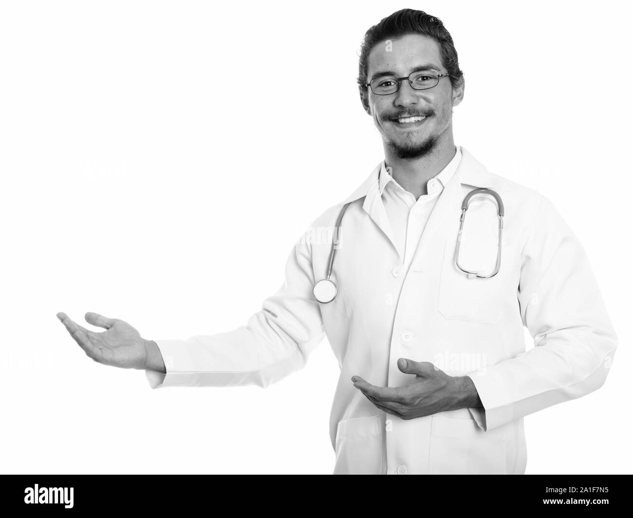 Studio shot of young happy man doctor smiling while showing something ...