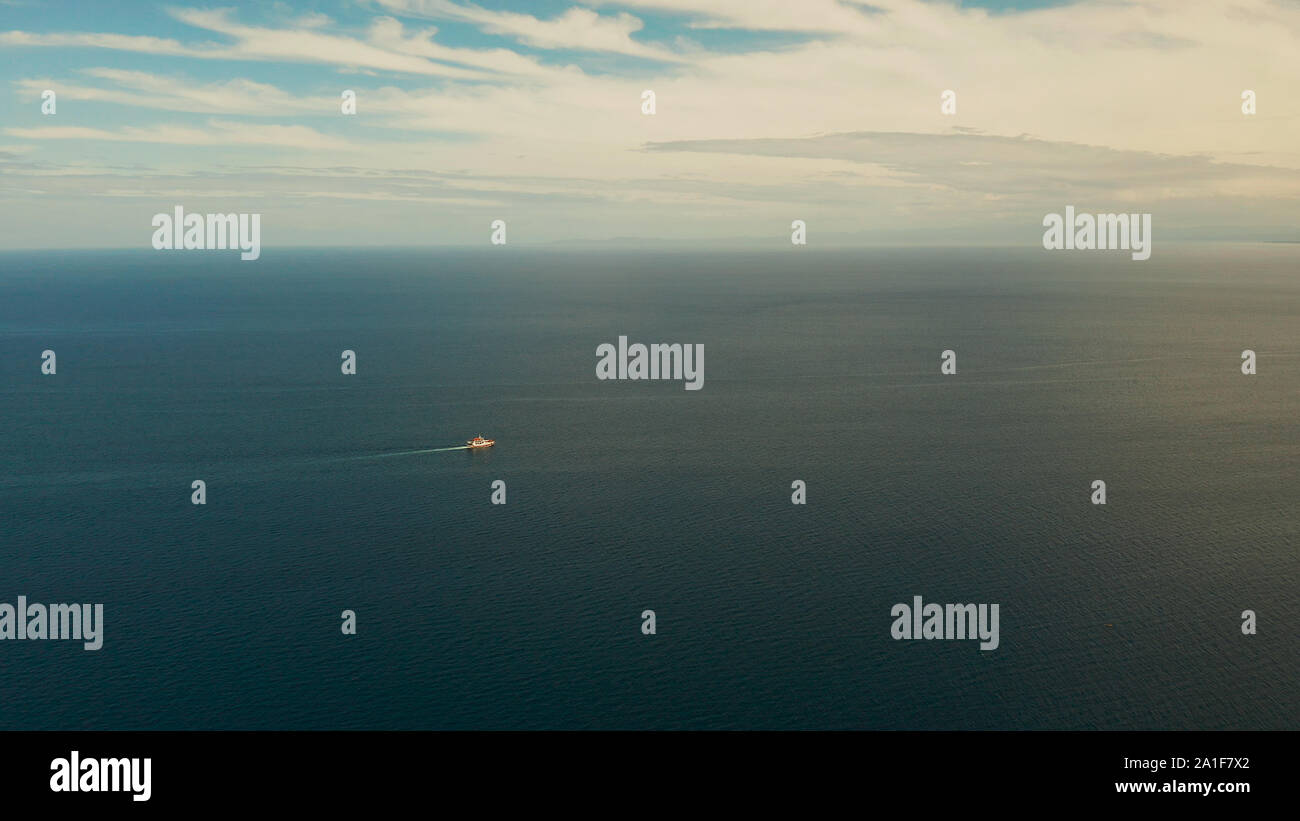 Small passenger ferry cruising in the open blue sea against blue sky ...