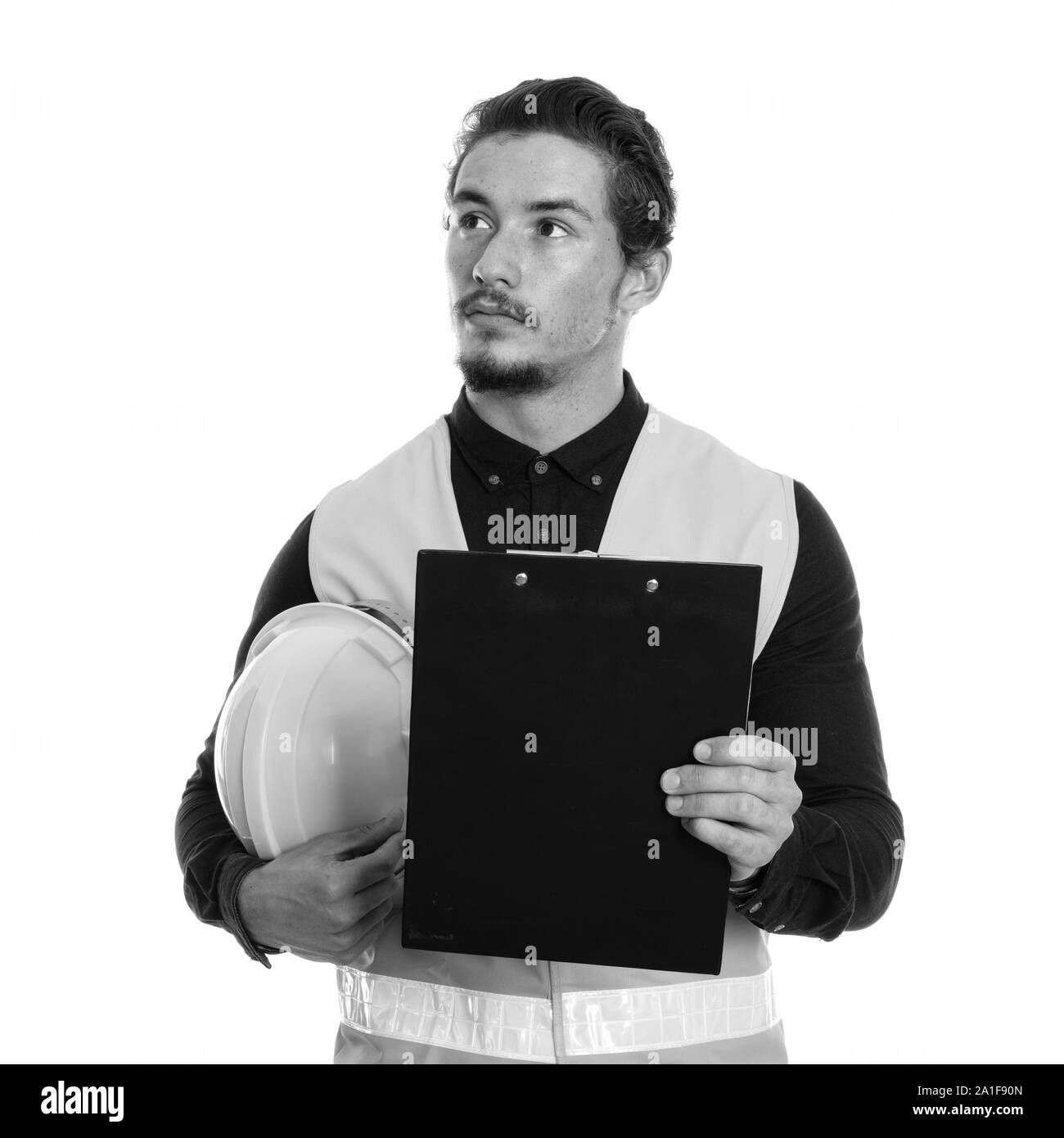 Studio shot of young handsome man construction worker thinking while ...