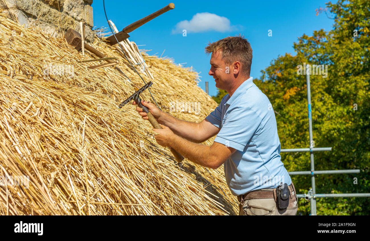 A Master Thatcher working on the roof of a village cottage repairing ...