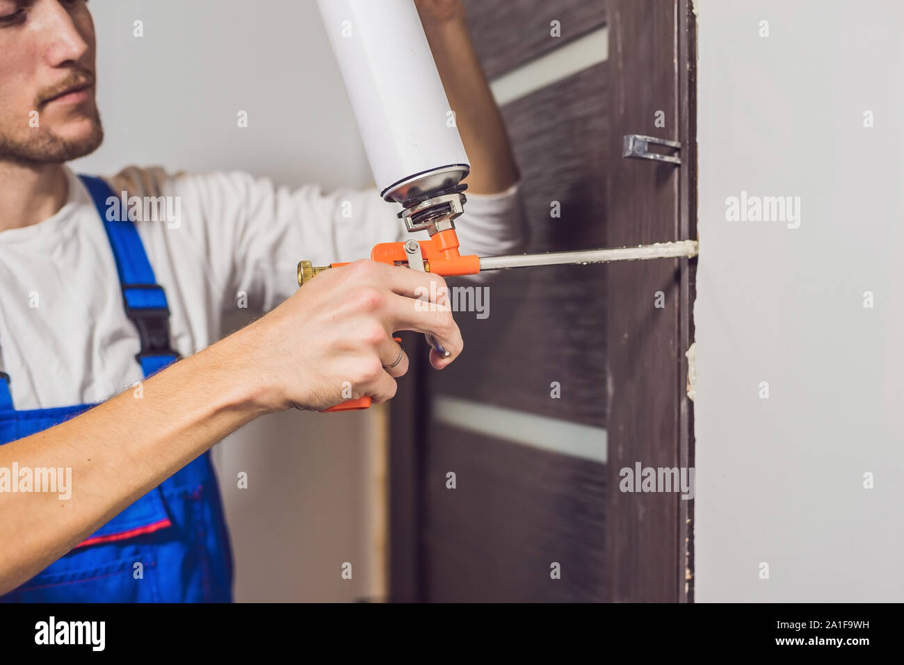 Young handyman installing door with an mounting foam in a room Stock ...