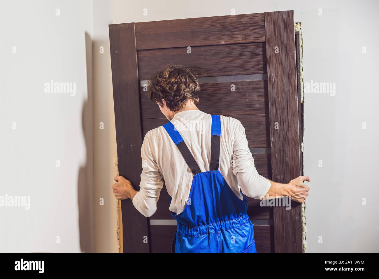 Young handyman installing door with an mounting foam in a room Stock ...