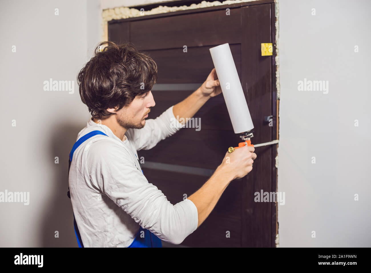 Young handyman installing door with an mounting foam in a room Stock ...