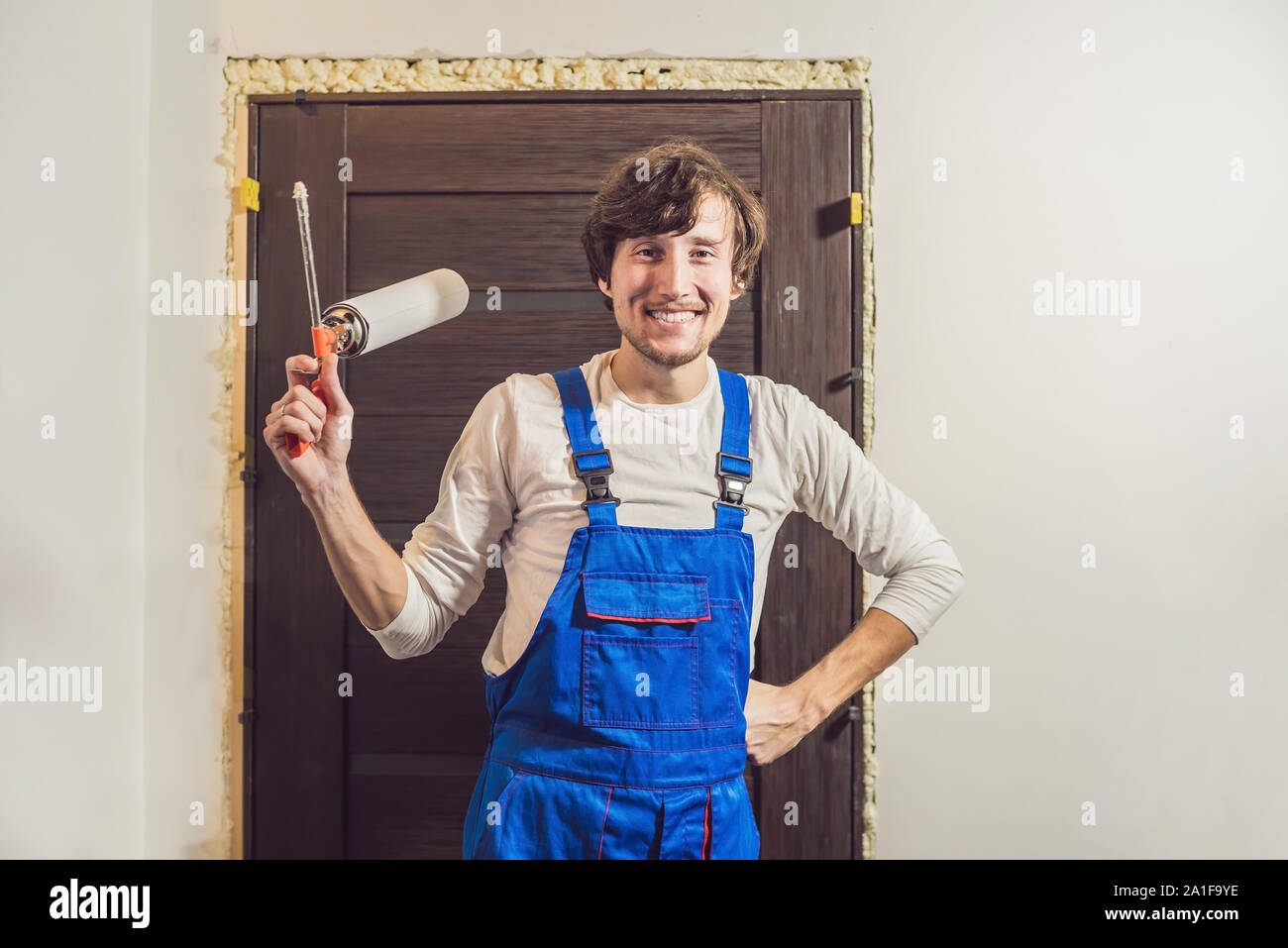 Young handyman installing door with an mounting foam in a room Stock ...