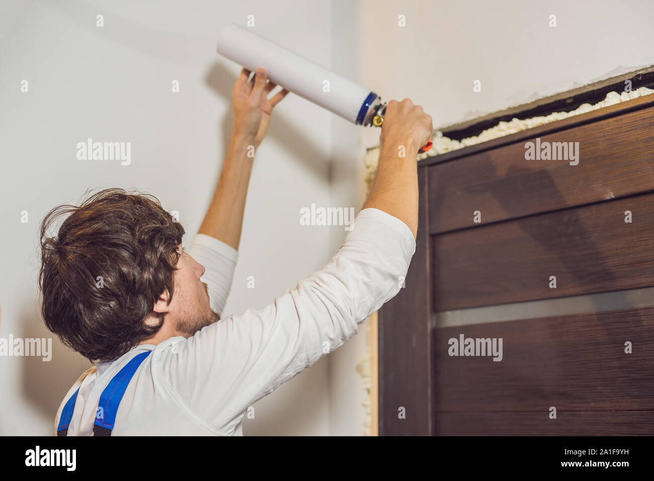 Young handyman installing door with an mounting foam in a room Stock ...