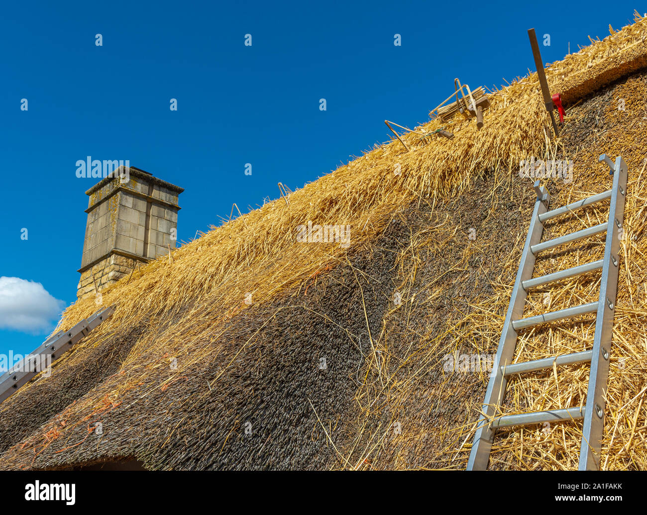 A thatcher’s tools on repaired and renewed straw thatch on the roof of ...