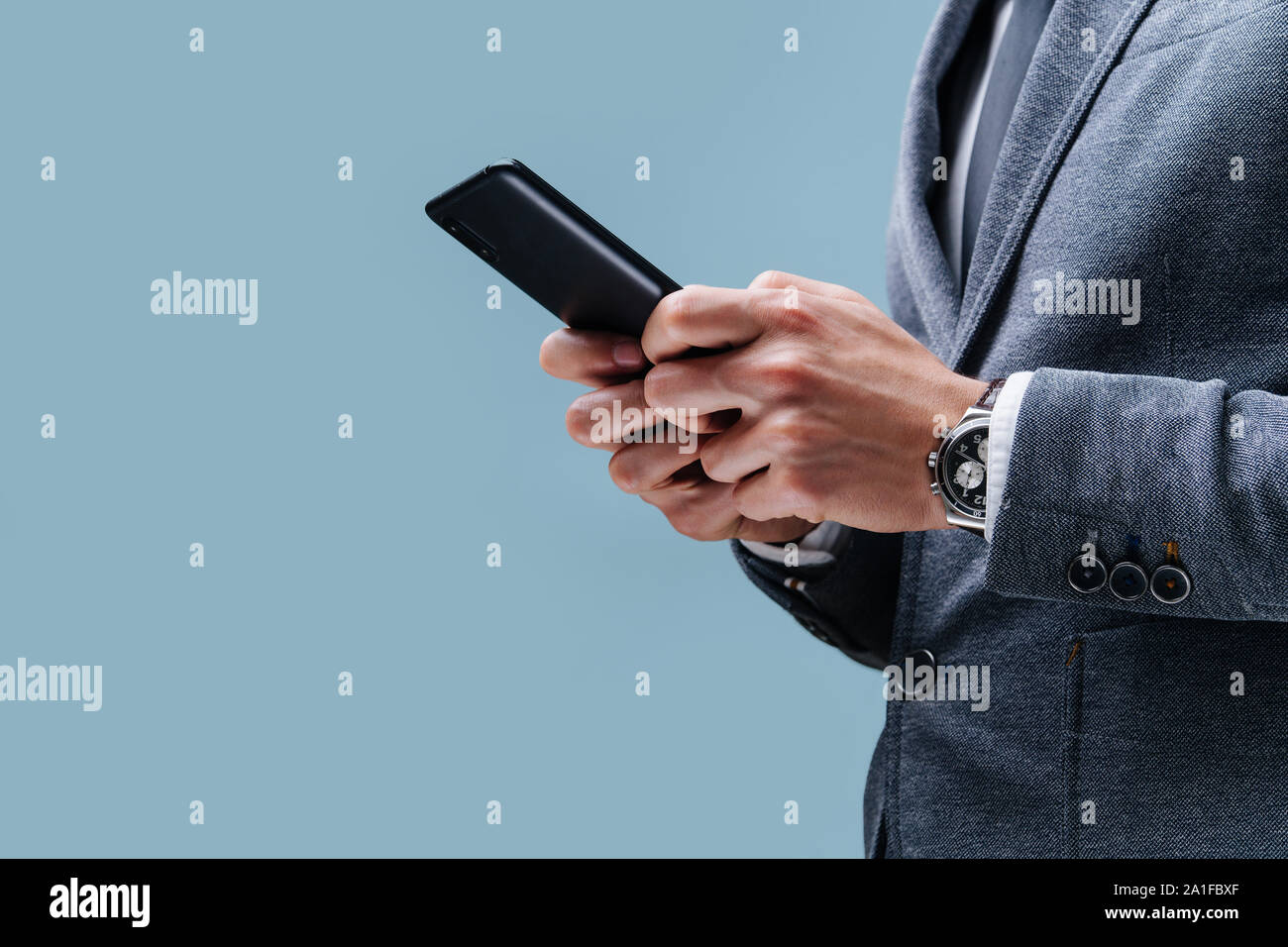 Businessman is typing a message on his smartphone over blue background ...