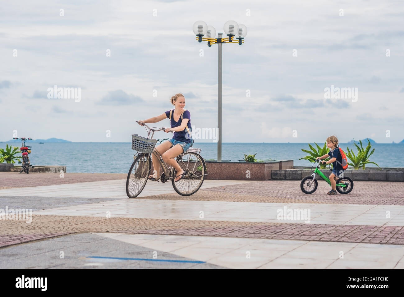 Happy family is riding bikes outdoors and smiling. Mom on a bike and ...