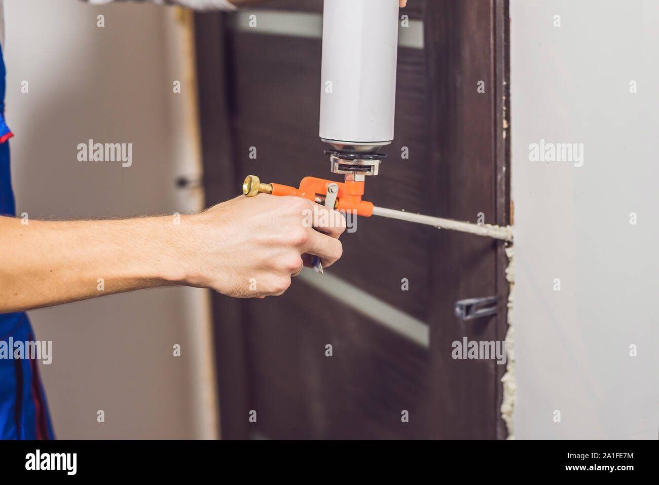 Young handyman installing door with an mounting foam in a room Stock ...