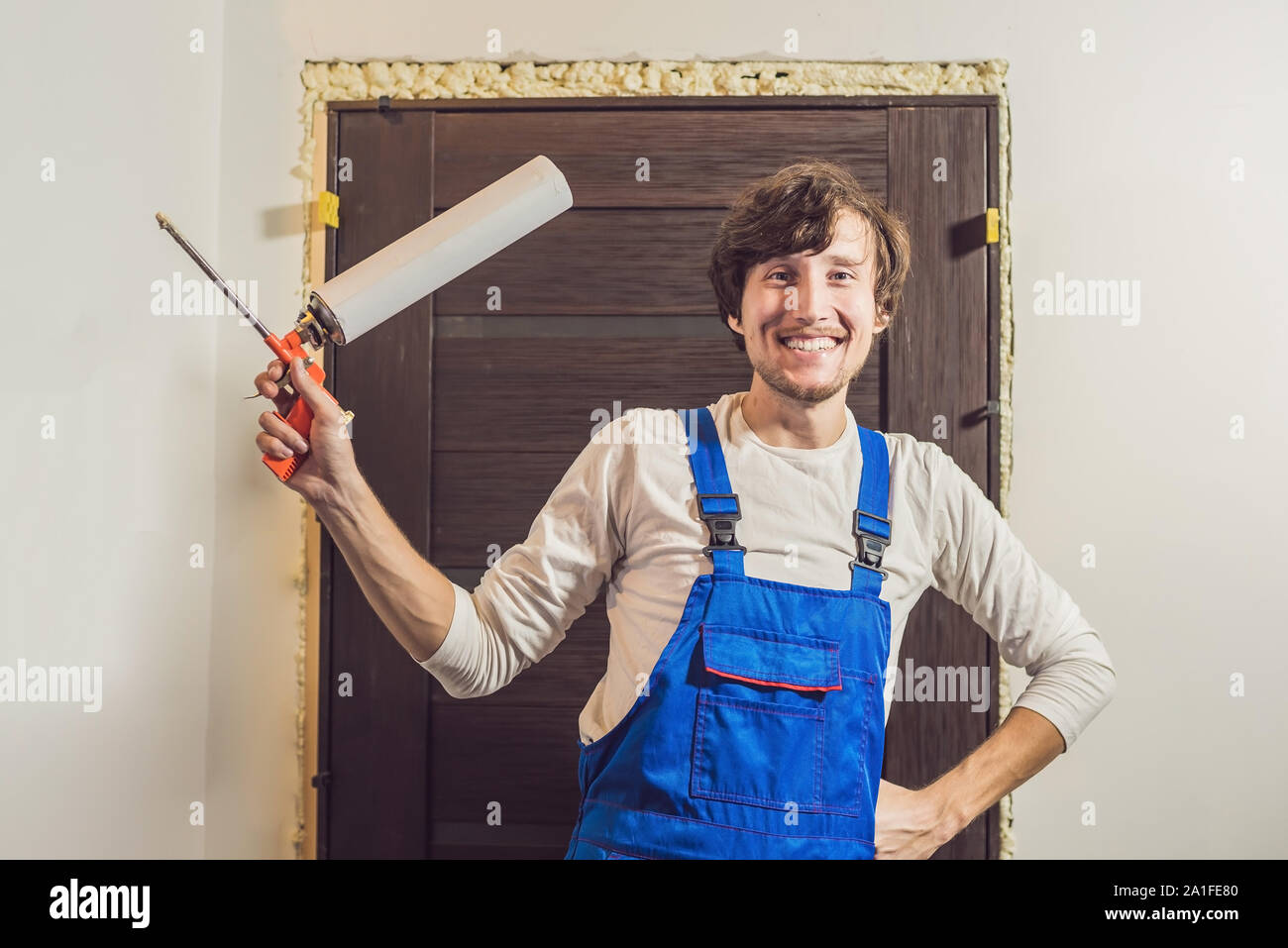 Young handyman installing door with an mounting foam in a room Stock ...